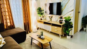 Uma sala de estar moderna com sofá, mesa de centro, TV e plantas decorativas.