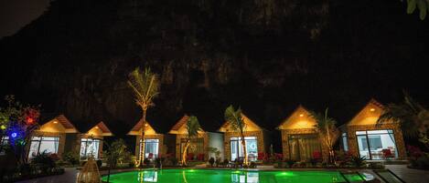 Resort com várias villas, piscina e montanhas ao fundo.
