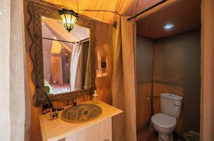 Um banheiro com lavatório de madeira, um espelho com moldura decorativa, sanita e cortina de chuveiro.