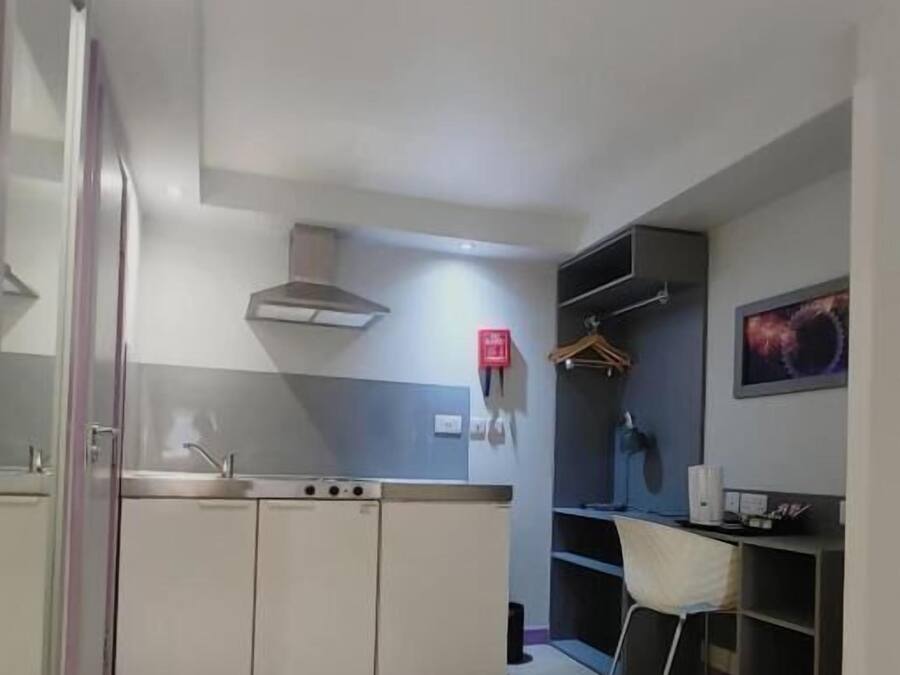 Cozinha moderna com armários brancos, pia de aço inoxidável e fogão embutido.