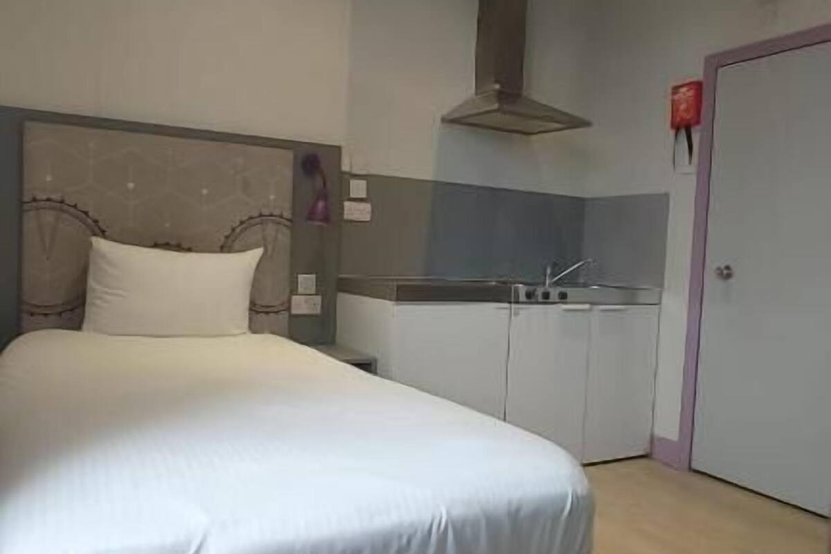 Quarto com cama, cozinha compacta e banheiro.