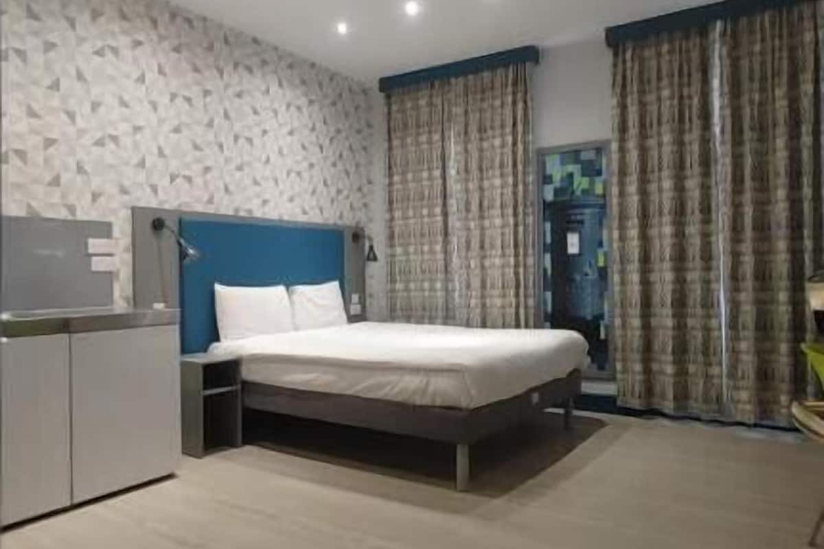 Quarto de hotel moderno com uma cama, uma escrivaninha e um guarda-roupa.