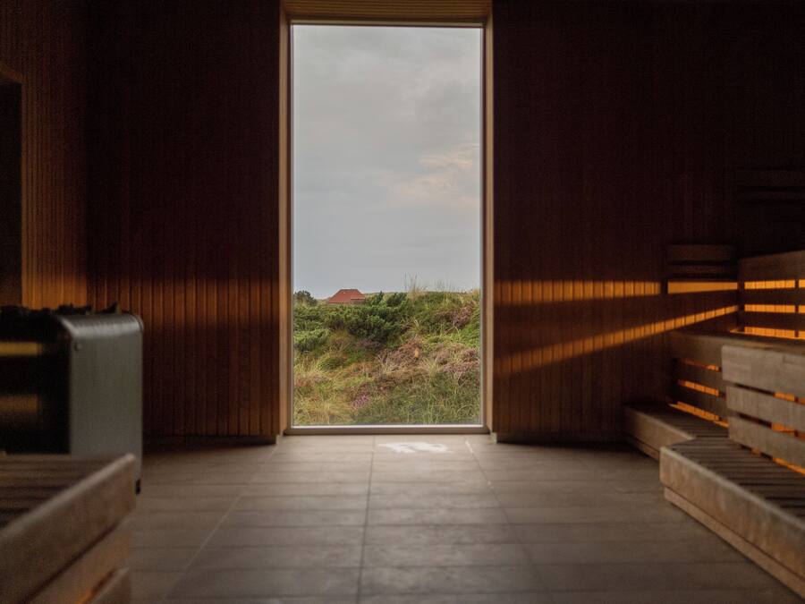 Quarto com uma janela grande, paredes de madeira, um banco e uma mala.