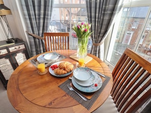 Uma mesa de jantar com pratos, croissants e um vaso de flores.