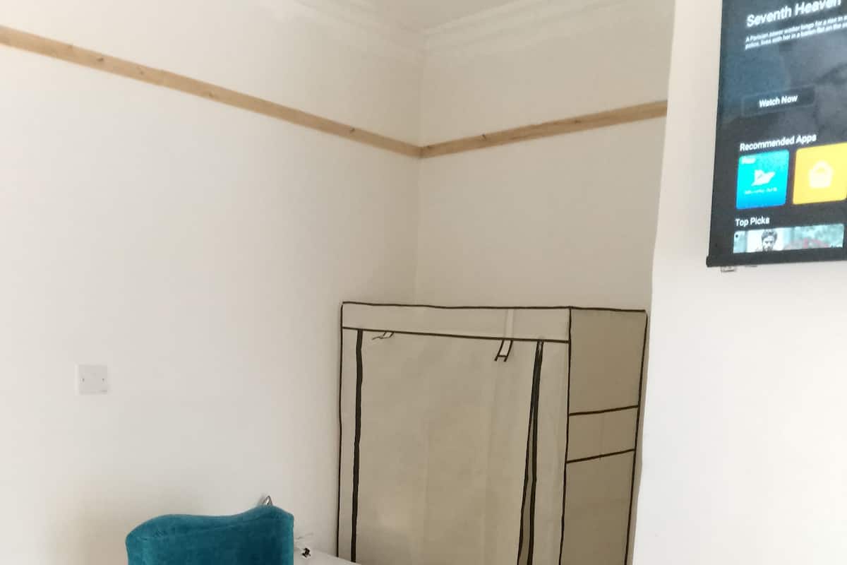 Quarto pequeno e bem organizado com escrivaninha, cadeira e guarda-roupa.