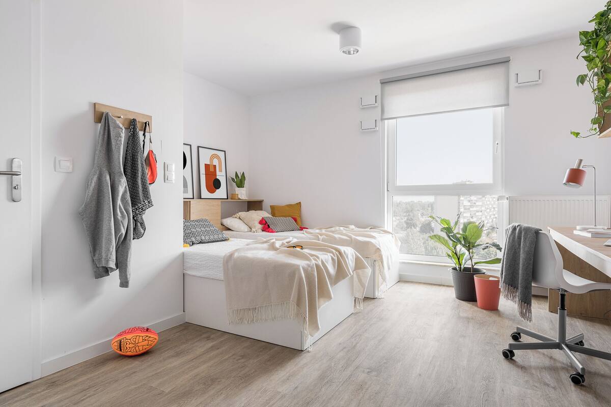 Quarto moderno com cama, escrivaninha e janela.