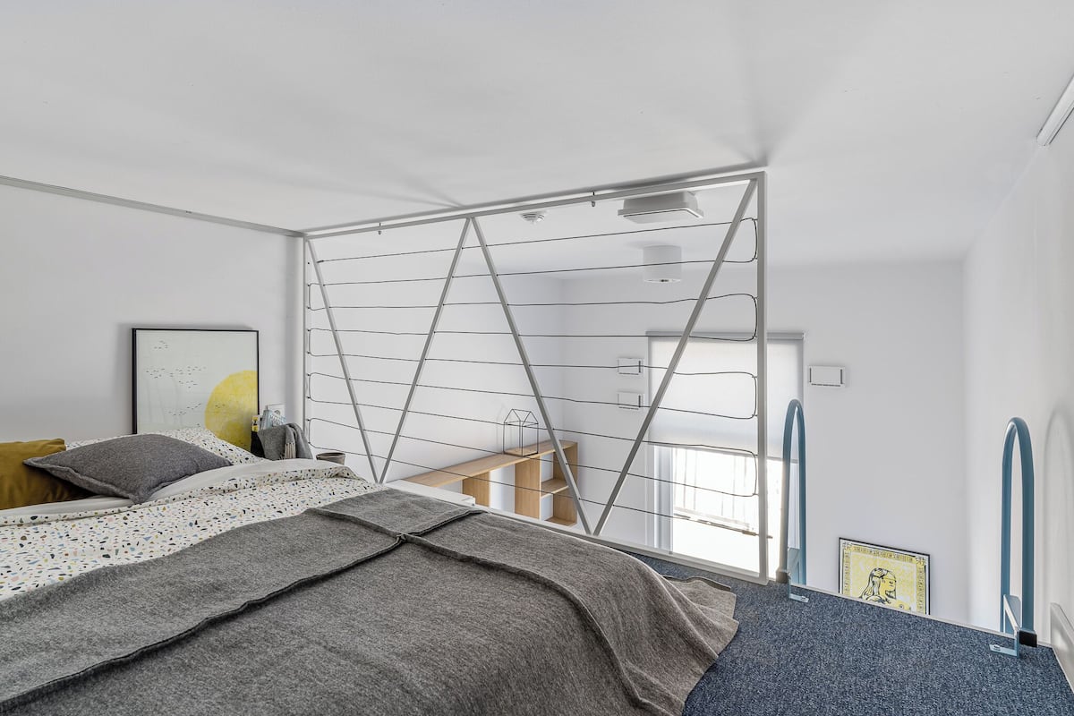 Quarto com cama, escada, escrivaninha e janela.