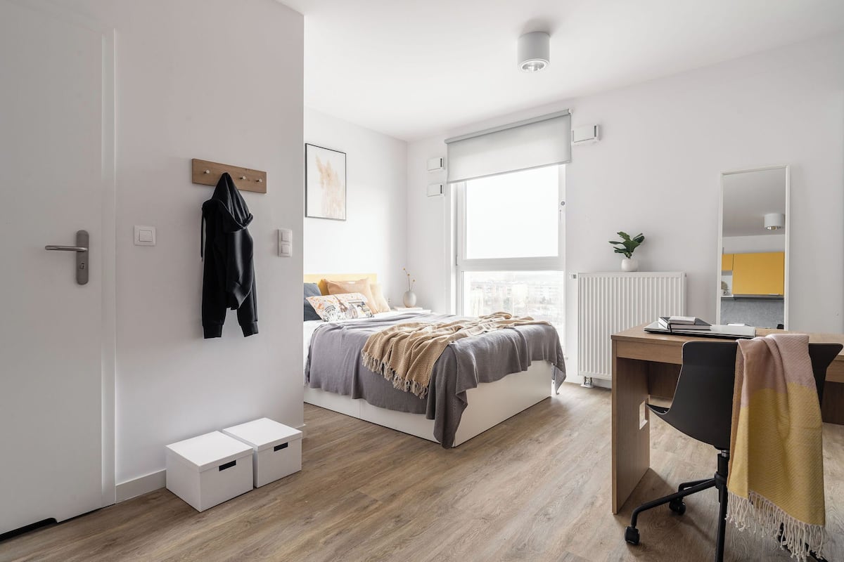 Quarto moderno com cama, escrivaninha e radiador.
