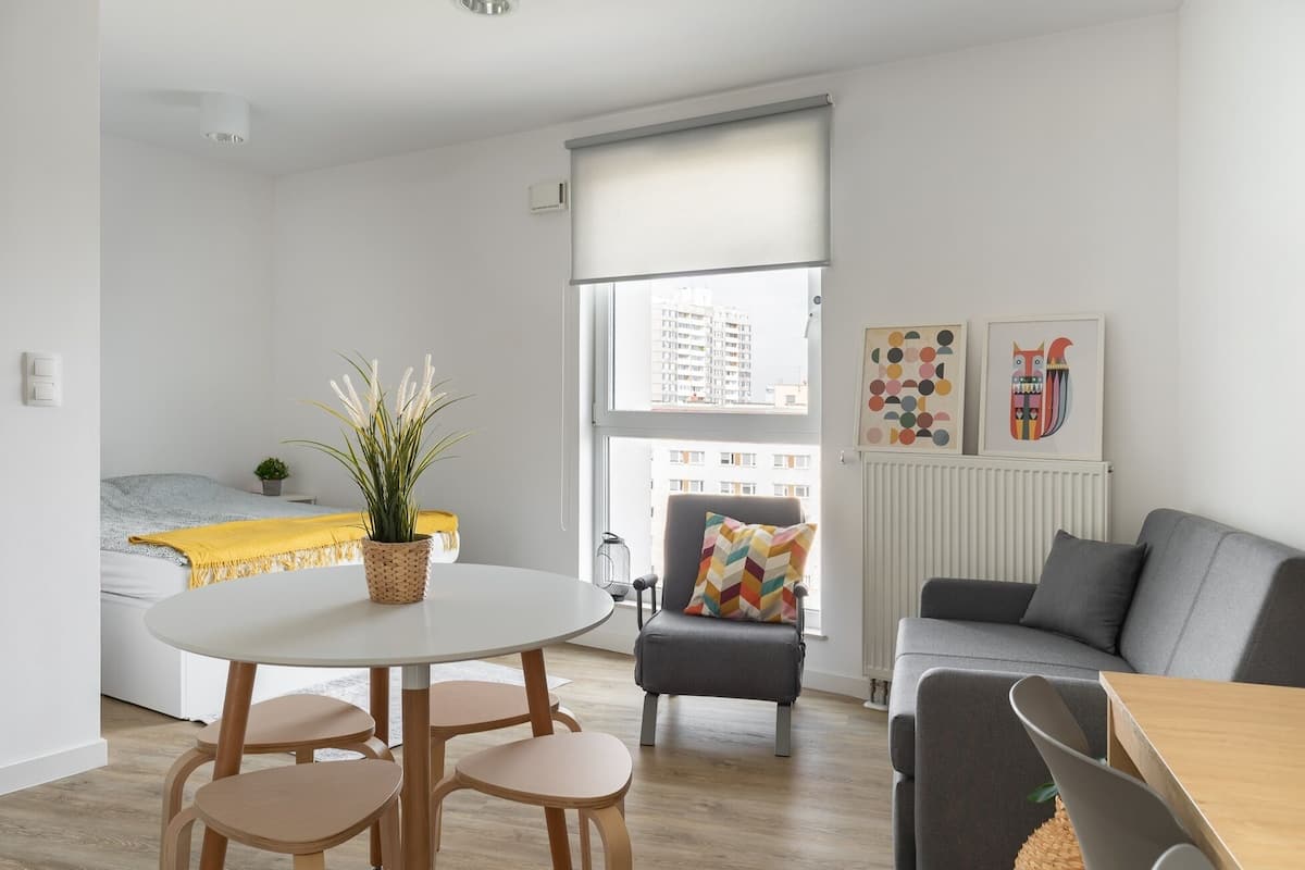 Uma sala de estar moderna com uma mesa de jantar redonda, sofá cinza e uma poltrona pequena.