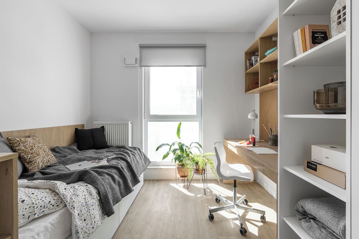 Quarto moderno com cama, escrivaninha, cadeira e estante.