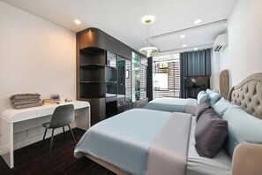 Quarto de hotel moderno com uma escrivaninha, duas camas, uma cadeira e uma televisão.