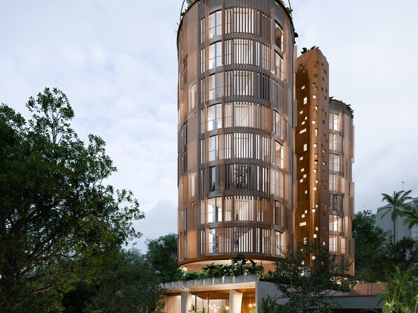 Um edifício moderno de vários andares com design cilíndrico, com varandas e grandes janelas.