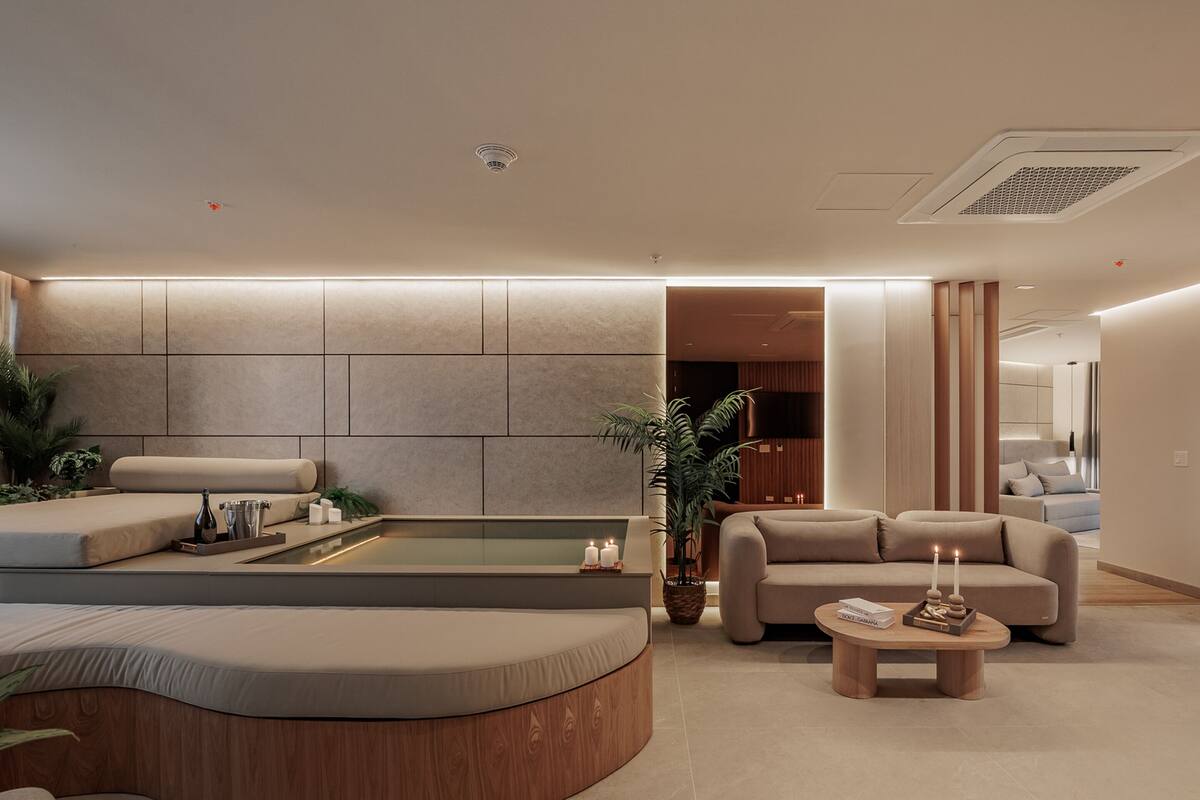 Uma sala de estar moderna com um espaço de estar circular, uma mesa de centro e uma pequena mesa lateral com velas.