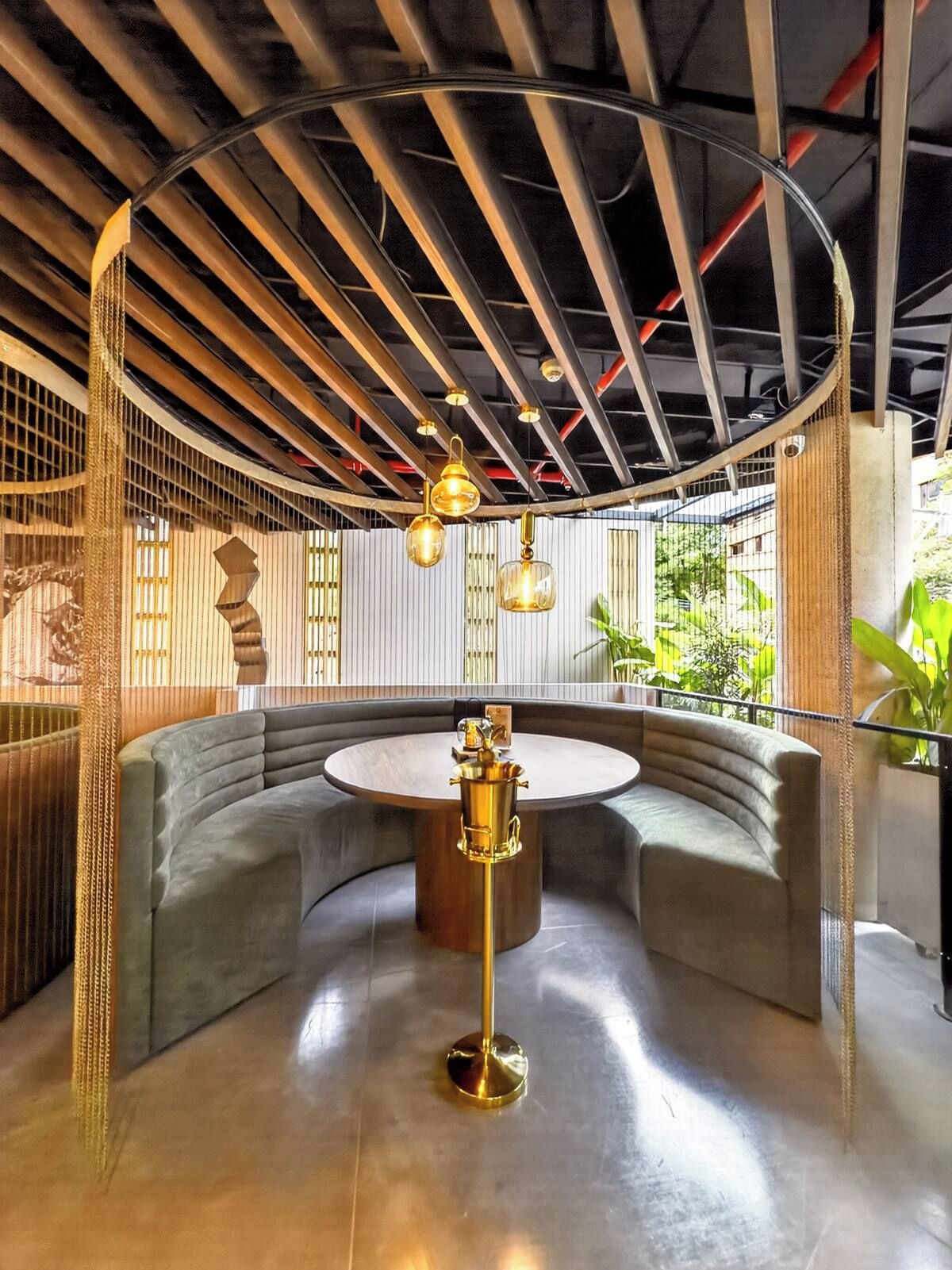 Um interior moderno com uma área de estar curva, uma mesa redonda central e um design de teto único com luminárias pendentes.