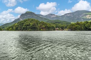 Um lago com uma montanha ao fundo e um pequeno edifício na margem.