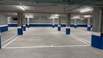 Garagem de estacionamento em vários níveis, com pilares de concreto e paredes pintadas em azul e branco.
