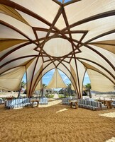 Uma cabana de praia com assentos listrados e estrutura de madeira em formato de estrela.
