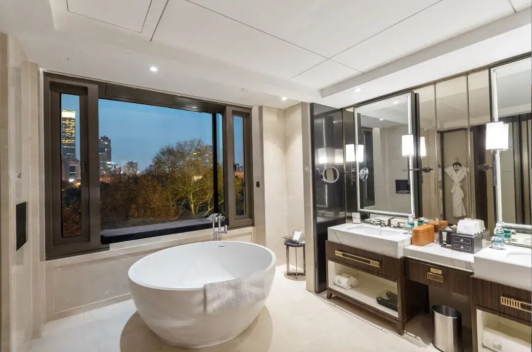 Uma casa de banho moderna com uma banheira grande, duas pias e um espelho amplo.