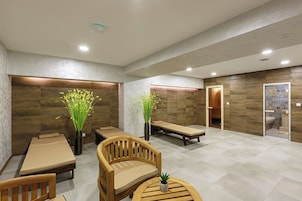 Um spa moderno com uma mesa de massagem, cadeiras de madeira e plantas em vasos.