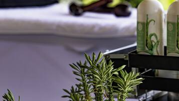 Uma cama com lençol branco, um par de óculos de sol e duas embalagens de loção em cima de uma mesa.