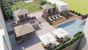 Área de piscina no terraço com espreguiçadeiras, guarda-sóis e um pequeno jardim.
