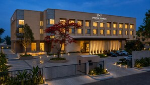 Um hotel moderno com entrada imponente, fachada bem iluminada e pátio ajardinado.