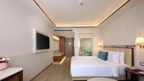 Quarto de hotel com cama, mesa de cabeceira, abajur, televisão e uma pequena mesa com um menu.