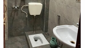 Casa de banho com sanita, lavatório e jarra de água.