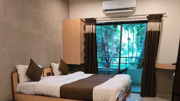 Quarto com cama, mesa de cabeceira, cadeira, ar condicionado e janela com cortinas.