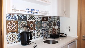 Uma cozinha com azulejos estampados, uma cafeteira, uma pia e armários.