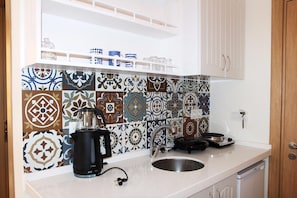 Uma cozinha com azulejos estampados, uma cafeteira, uma pia e armários.