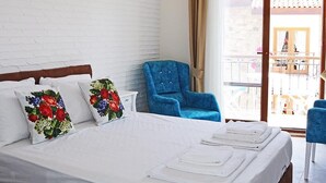 Quarto com cama, ventilador de teto, uma cadeira e vista para o exterior.