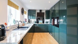 Uma cozinha moderna com bancada de mármore, piso de madeira e forno embutido.