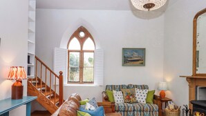Uma sala de estar aconchegante com uma escada de madeira, lareira e uma janela grande com persianas.