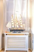 Um modelo de navio sobre uma mesa branca, com uma janela ao fundo.