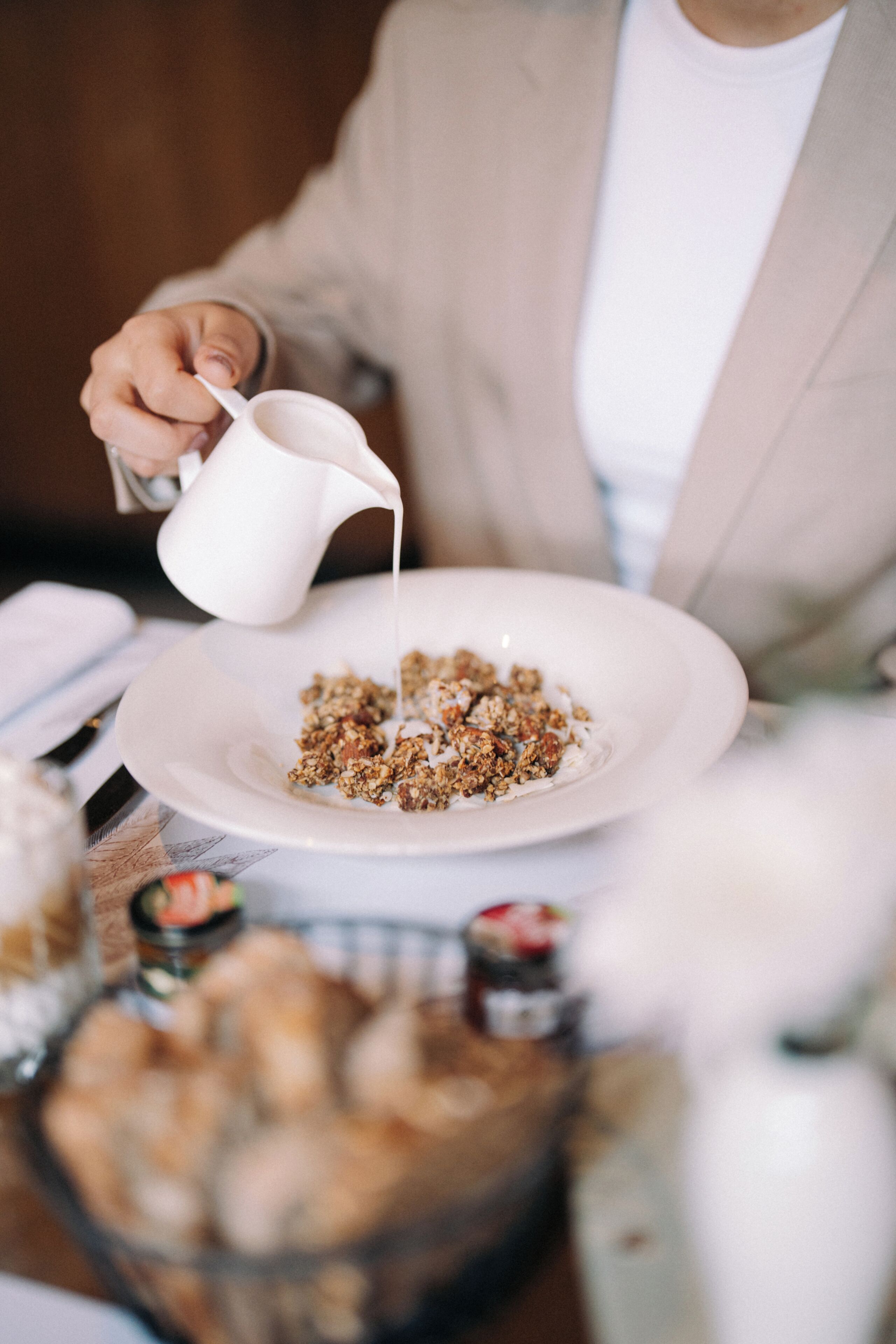 Uma pessoa a verter leite para uma tigela de granola.