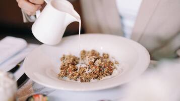 Uma pessoa a verter leite para uma tigela de granola.