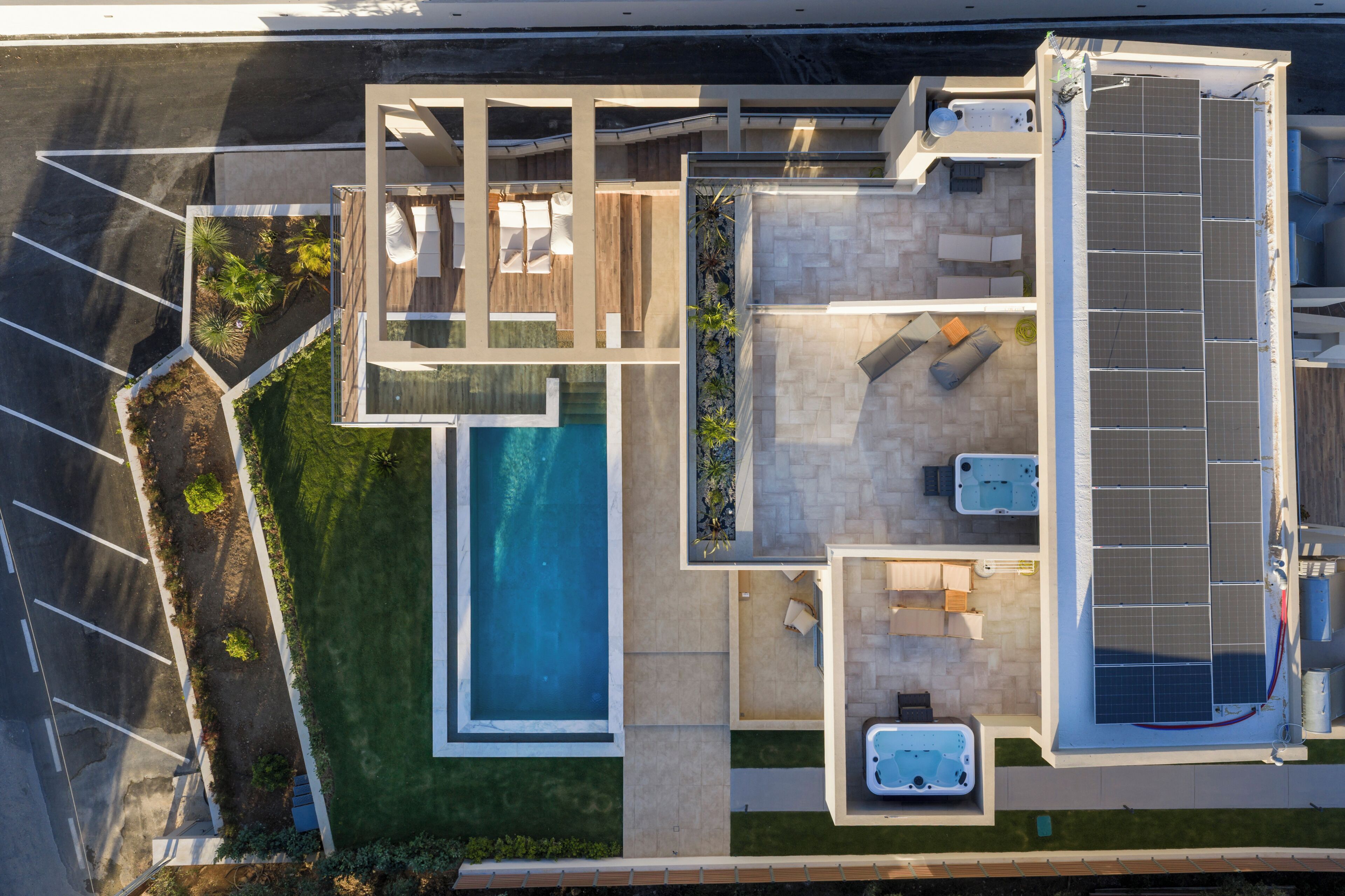 Vista aérea de uma casa moderna com piscina, área de estar ao ar livre e painéis solares.