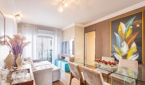 Uma sala de estar moderna com uma mesa de jantar de vidro, um sofá e um quadro grande na parede.