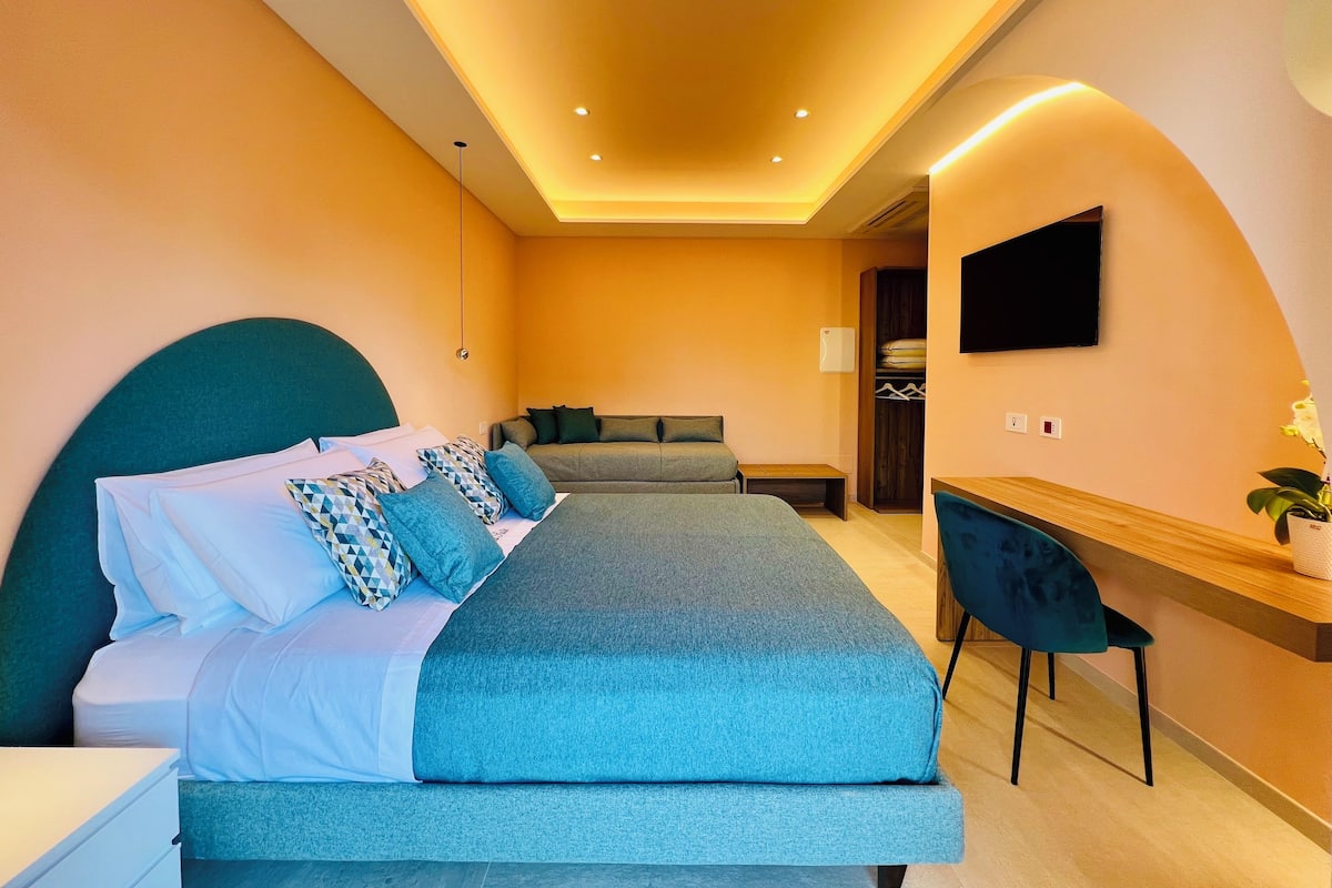 Quarto de hotel moderno com cama, escrivaninha e televisão.