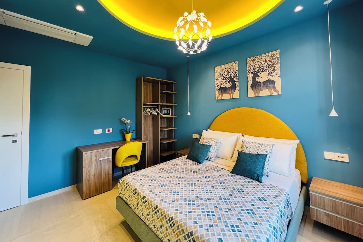 Um quarto com cama, escrivaninha e guarda-roupa.