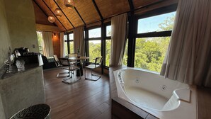 Quarto com uma janela grande, teto de madeira, banheira e área de jantar com cadeiras e mesa.