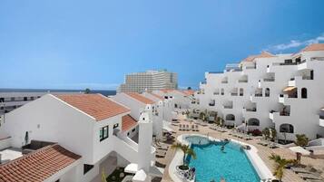 Um resort com piscina, edifícios brancos e vista para o oceano.