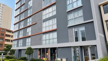 Um edifício de vários andares com design arquitetônico moderno, destacando uma entrada imponente com portas de vidro e o número do endereço visível.
