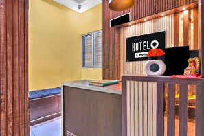 Uma mesa de recepção com uma placa que diz 'HOTEL' e um vaso decorativo com flores.