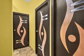 Um corredor com três portas, cada uma exibindo um design abstrato singular.