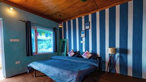 Quarto com cama, janela, luminária e parede com listras verticais.