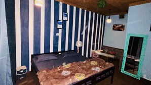 Quarto com uma cama, uma mesinha de cabeceira, luminária pendente e parede com padrão listrado.
