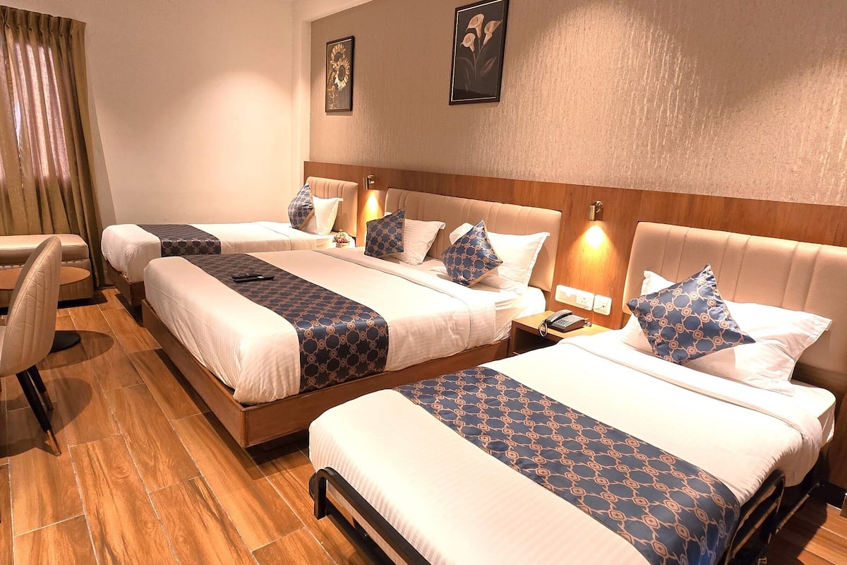 Quarto de hotel com duas camas, uma escrivaninha, uma cadeira e uma televisão.