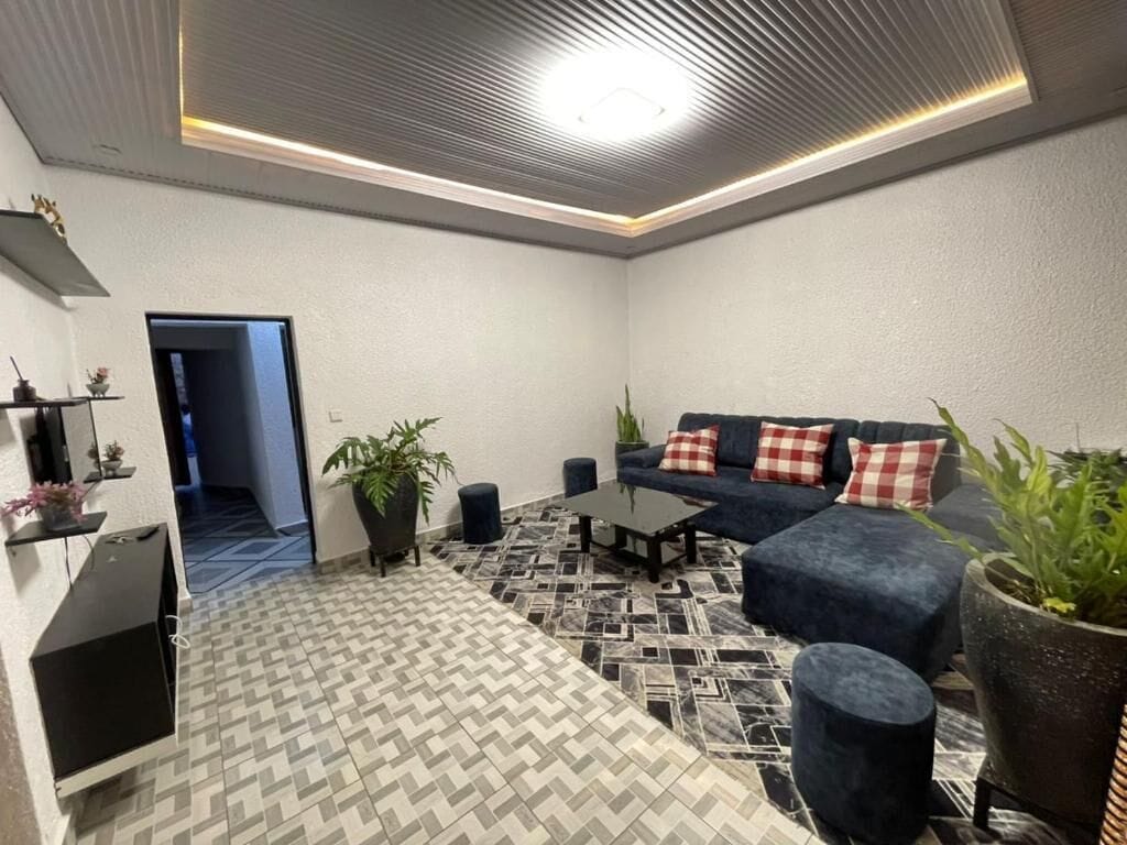 Uma sala de estar moderna com um sofá, mesa de centro e plantas em vasos.